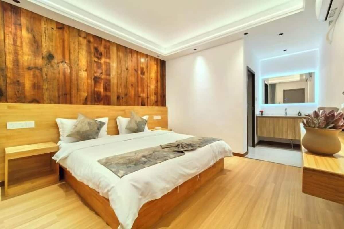 Quarto moderno com cabeceira de madeira, uma cama grande, uma mesa de cabeceira e um criado-mudo.