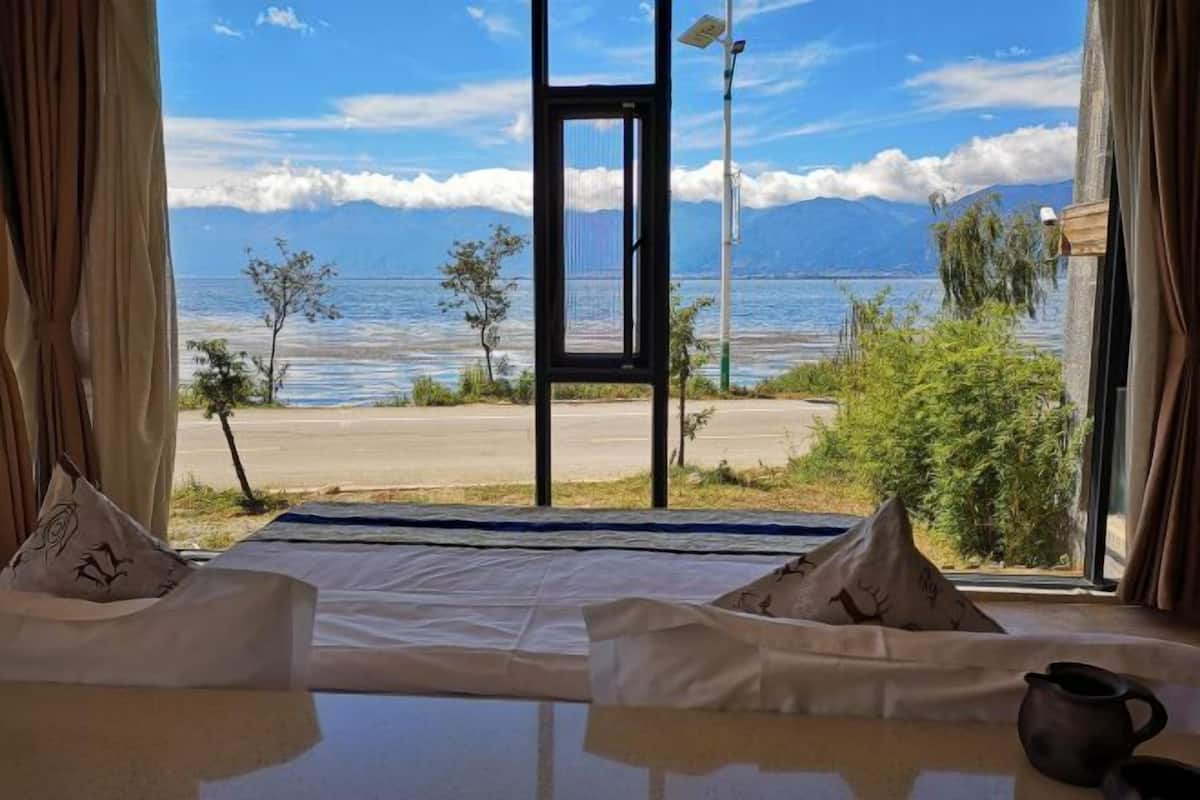 Quarto com uma cama virada para uma vista panorâmica de um lago e montanhas.