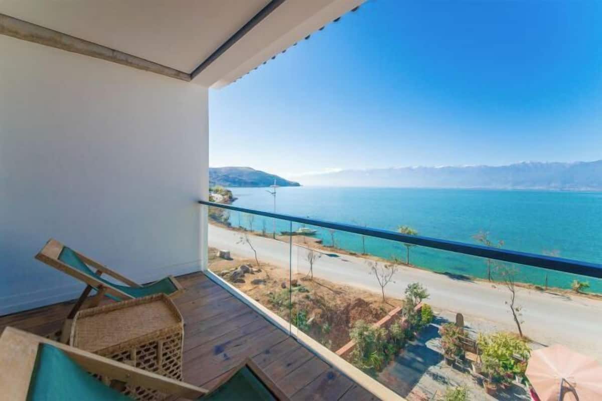 Uma varanda com vista para o mar, móveis de madeira e plantas em vasos.