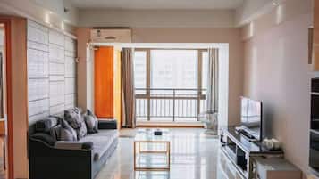 Uma sala de estar moderna com um sofá, TV e uma mesa de centro de vidro.