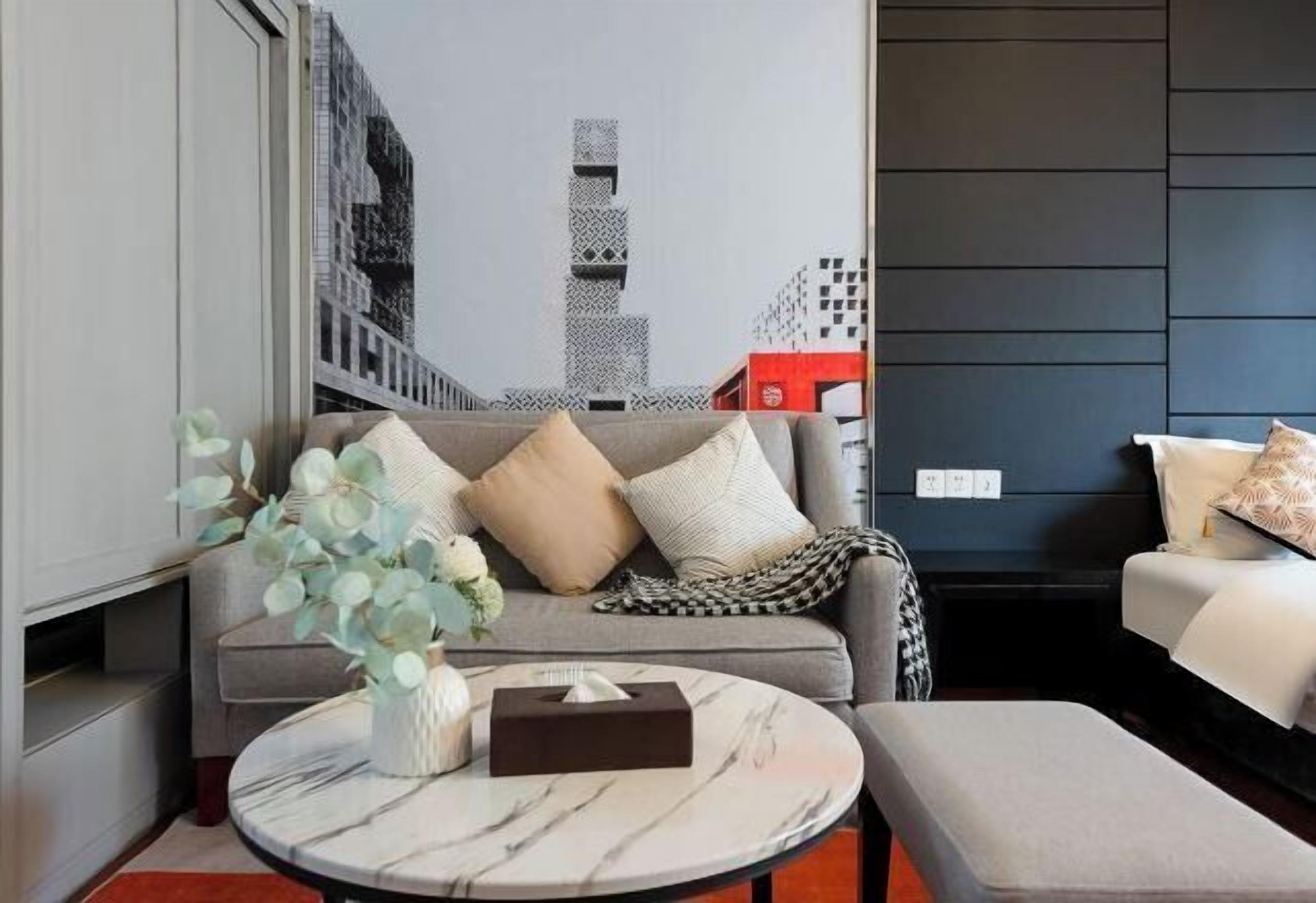 Uma sala de estar moderna com um sofá, uma mesa de centro redonda e um vaso decorativo.