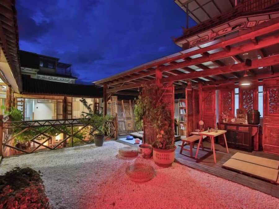 Um edifício em estilo japonês tradicional com área de estar coberta, estrutura de madeira e plantas em vasos.