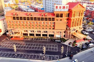 Um hotel de vários andares com telhado vermelho e um estacionamento em frente.