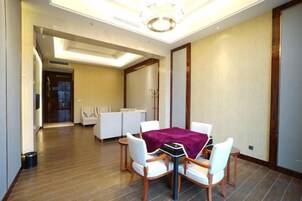 Quarto de hotel moderno com área de jantar, um sofá e piso de madeira.