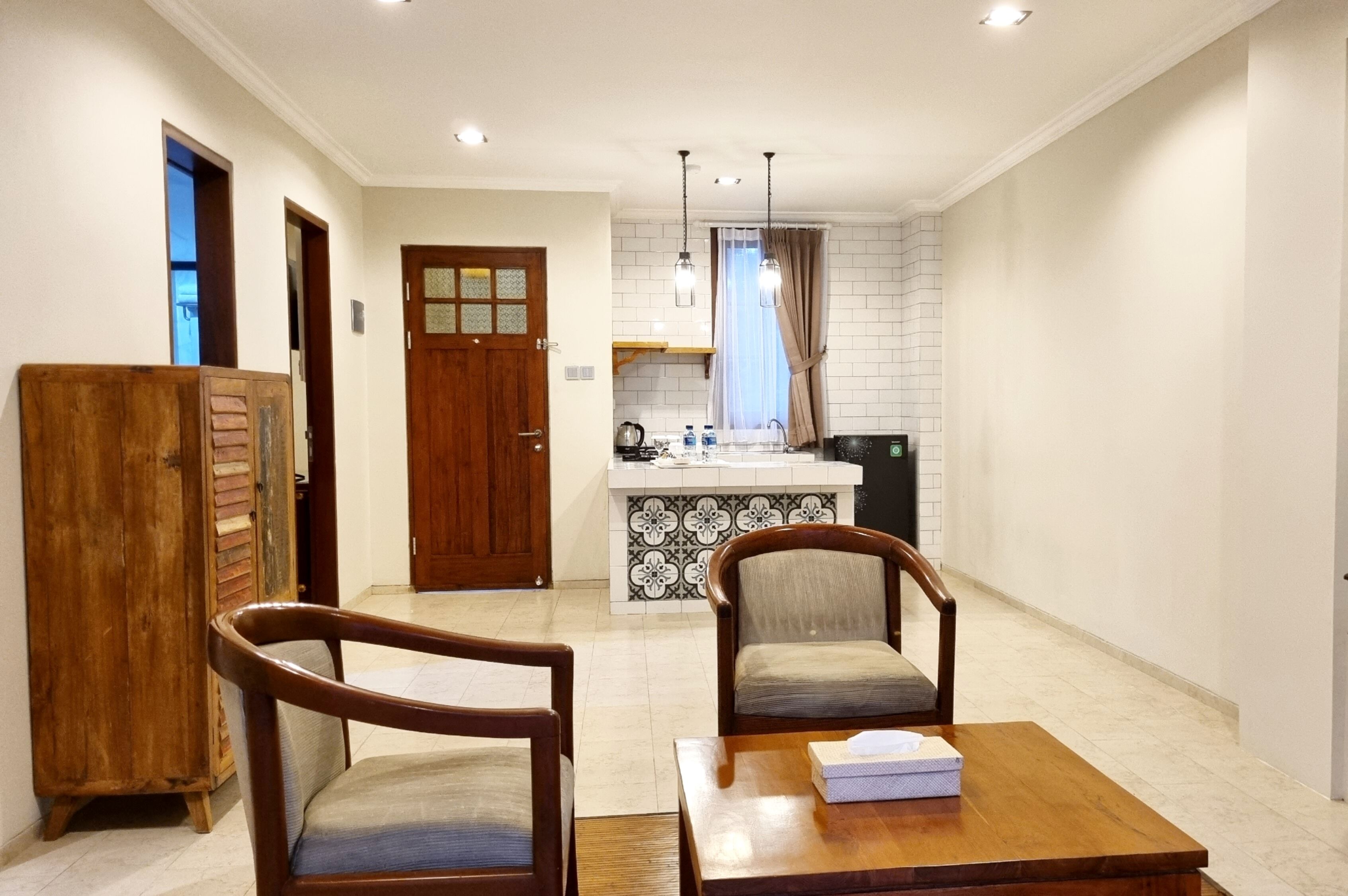 Cozinha moderna com bancada branca, armário de madeira e área de refeições com duas cadeiras e uma mesa de madeira.