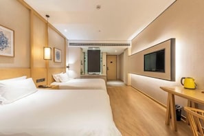 Quarto de hotel com duas camas, televisão, secretária e máquina de café.