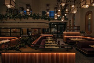 Um restaurante com várias áreas de estar, incluindo cabines e mesas, e um bar com balcão.