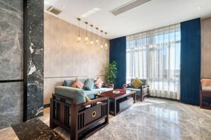 Uma sala de estar moderna com sofá, mesa de centro e uma grande janela com cortinas.