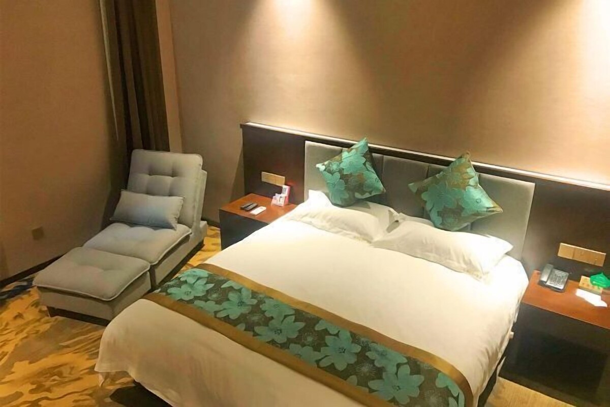 Quarto de hotel com uma cama, um sofá-cama e uma mesa de cabeceira com um telefone.
