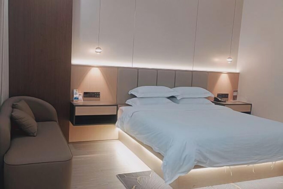 Quarto moderno com cama, mesas de cabeceira e um banco.