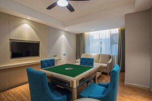 Quarto com mesa de bilhar, assentos confortáveis, TV de tela plana e ventilador de teto.