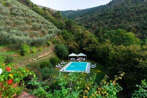 Uma piscina rodeada por vegetação exuberante e colinas.