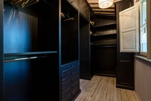 Um closet espaçoso com armários em madeira escura, uma barra para pendurar roupas e um luminário no teto.