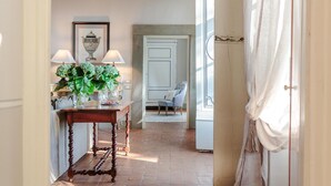 Um corredor com uma mesa de madeira, duas luminárias, um quadro emoldurado e uma cadeira.
