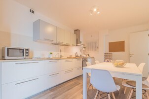 Uma cozinha moderna com armários brancos, um micro-ondas e uma mesa de jantar com cadeiras.