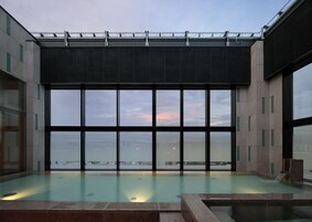 Uma piscina interior moderna com amplas janelas que oferecem vista para a paisagem urbana.