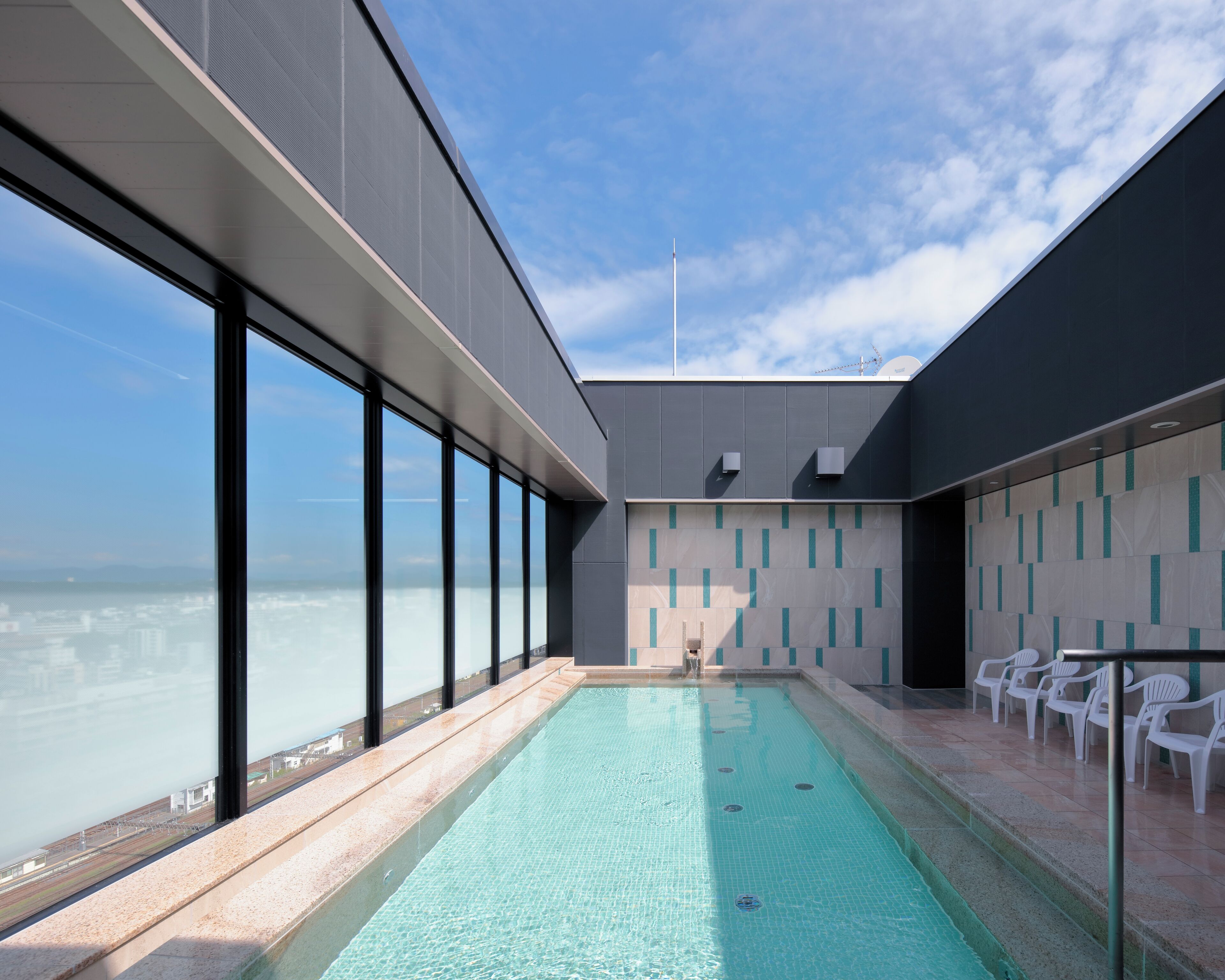 Piscina interior moderna com grandes janelas e vista para a cidade.