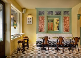 Uma área de refeições com piso estampado, parede verde decorativa e obras de arte emolduradas.