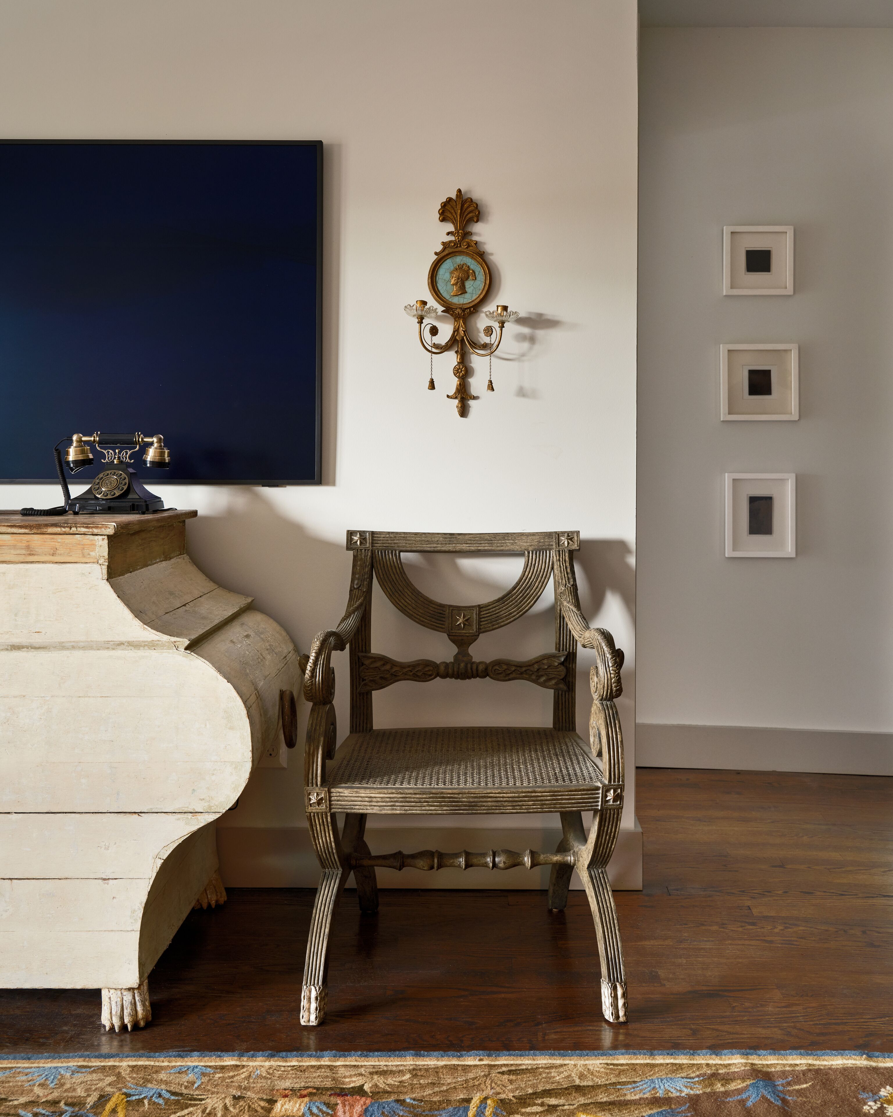 Quarto com telefone antigo, um objeto decorativo na parede e um quadro emoldurado.