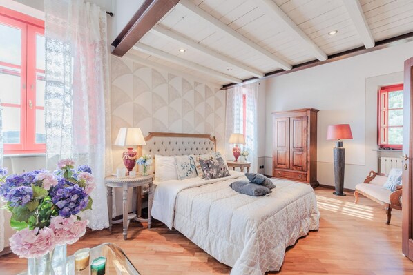 Um quarto com cama, mesas de cabeceira, cómoda e uma cadeira.