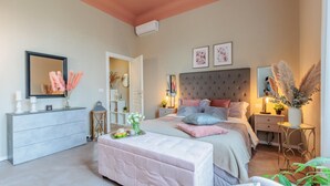 Quarto com cama, mesas de cabeceira, cômoda e espelho.