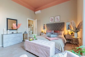 Quarto com cama, mesas de cabeceira, cômoda e espelho.
