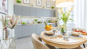 Uma cozinha moderna com armários cinza, uma mesa de jantar posta com pratos, copos e flores.