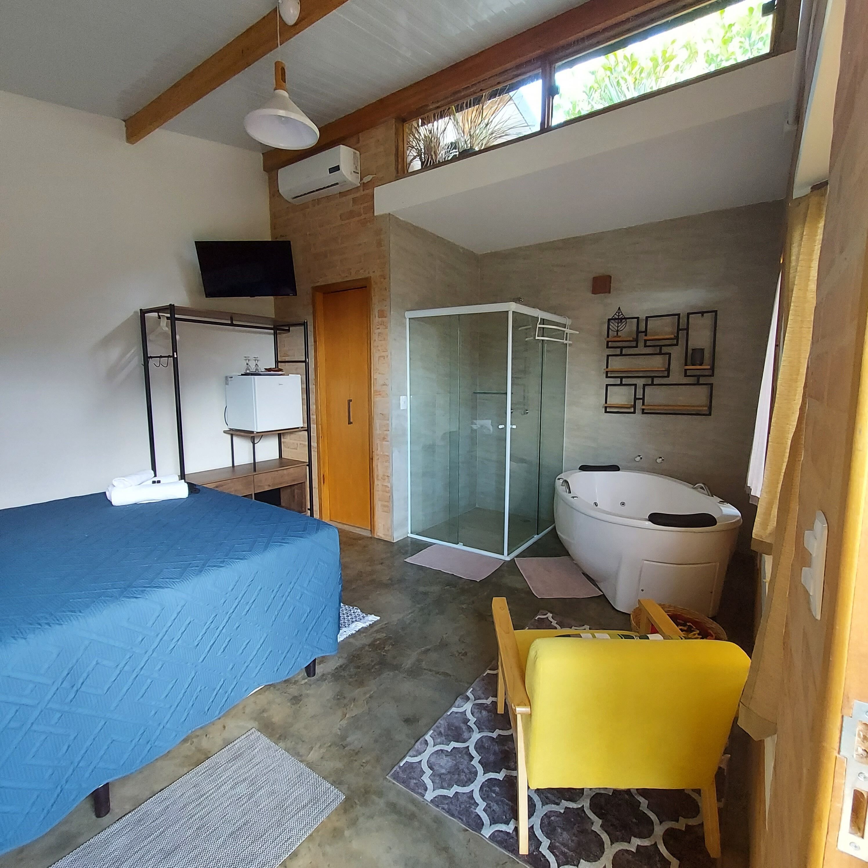 Quarto com cama, escrivaninha, cadeira, chuveiro e banheira.