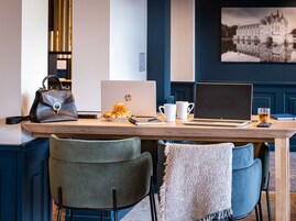 Uma mesa de madeira com laptops, uma bolsa, croissants e xícaras de café.