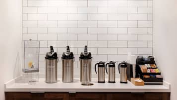 Uma estação de café com várias máquinas de café e um dosador de café em uma bancada branca.