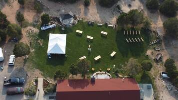 Vista aérea de um camping com barracas, área de refeições e uma tenda grande.