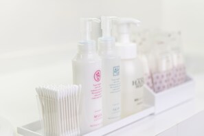 Uma fileira de produtos de cuidados com a pele sobre uma estante branca.
