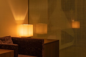 Quarto com sofá e duas luminárias fixadas na parede.