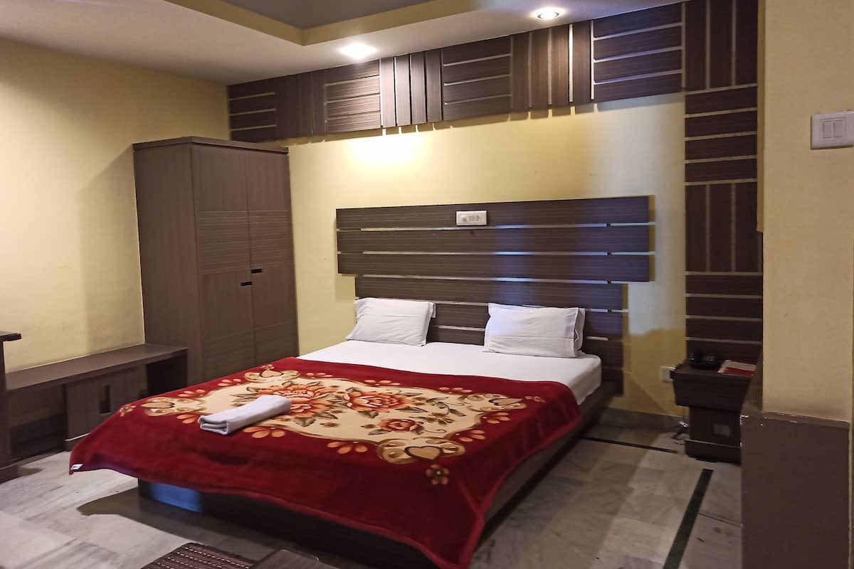 Quarto de hotel com uma cama, um guarda-roupa e uma mesa de cabeceira.