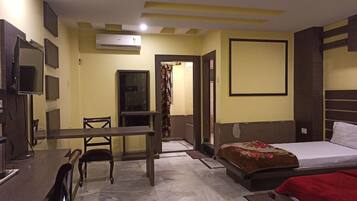 Quarto de hotel com cama, escrivaninha, cadeira, televisão e ar condicionado.