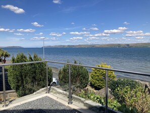 Uma varanda com vista para um lago, rodeada por vegetação e um corrimão de metal.