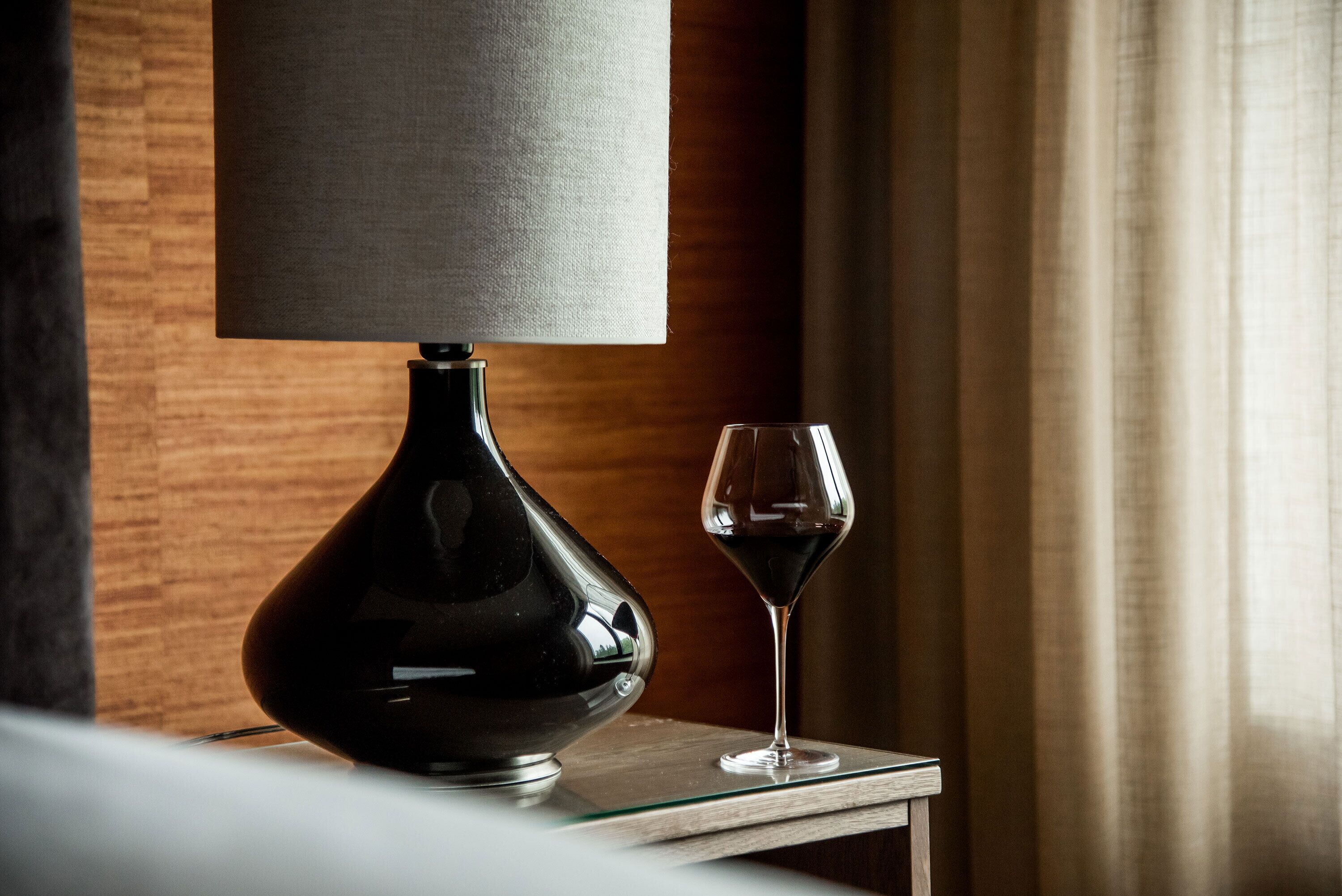 Uma lâmpada e uma taça de vinho sobre uma mesa de cabeceira.