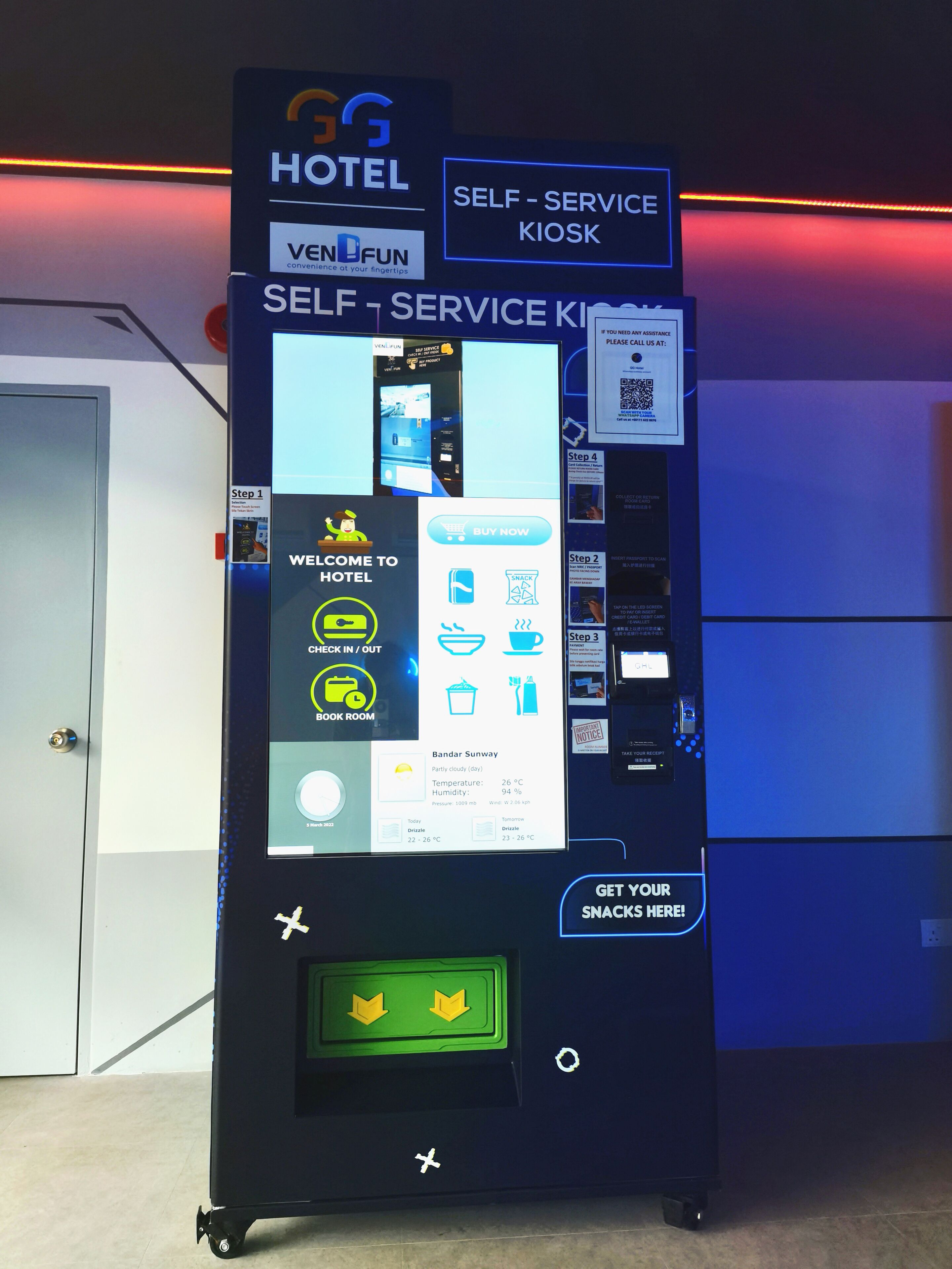 Quiosque de autoatendimento em hotel, com opções para registo/saída, reserva de quartos e compra de snacks.