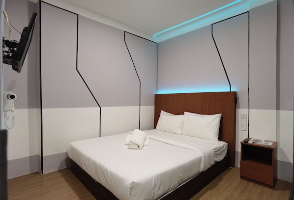 Quarto de hotel moderno com cama bem arrumada, cabeceira de madeira e mesa de cabeceira com telefone e papéis.
