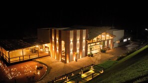 Um edifício moderno com fachada de vidro, um pátio e uma piscina.