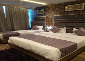Quarto de hotel com duas camas, cabeceira de madeira, parede estampada e janela com cortinas.