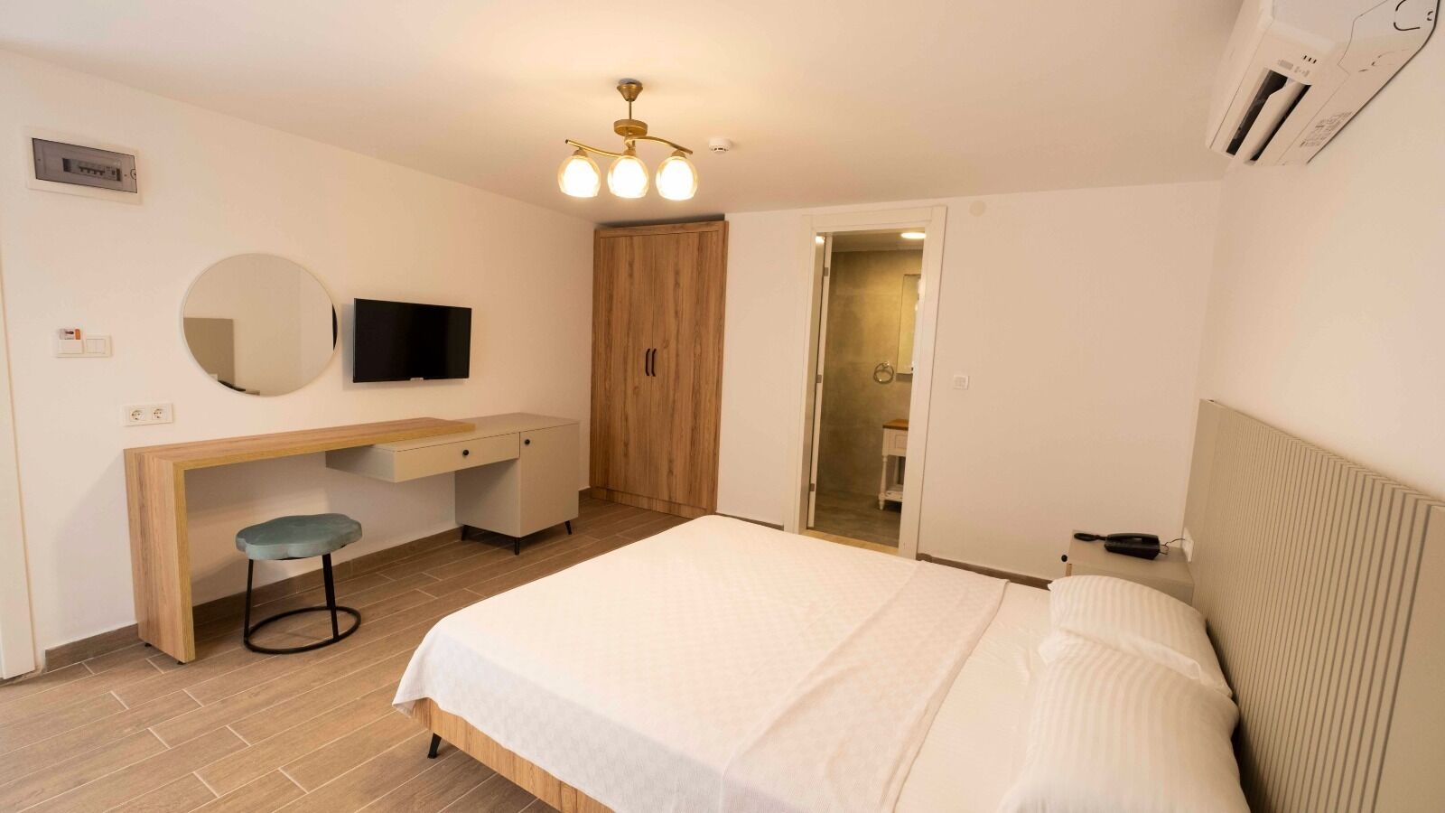 Quarto com cama, escrivaninha, cadeira, televisão e armário.
