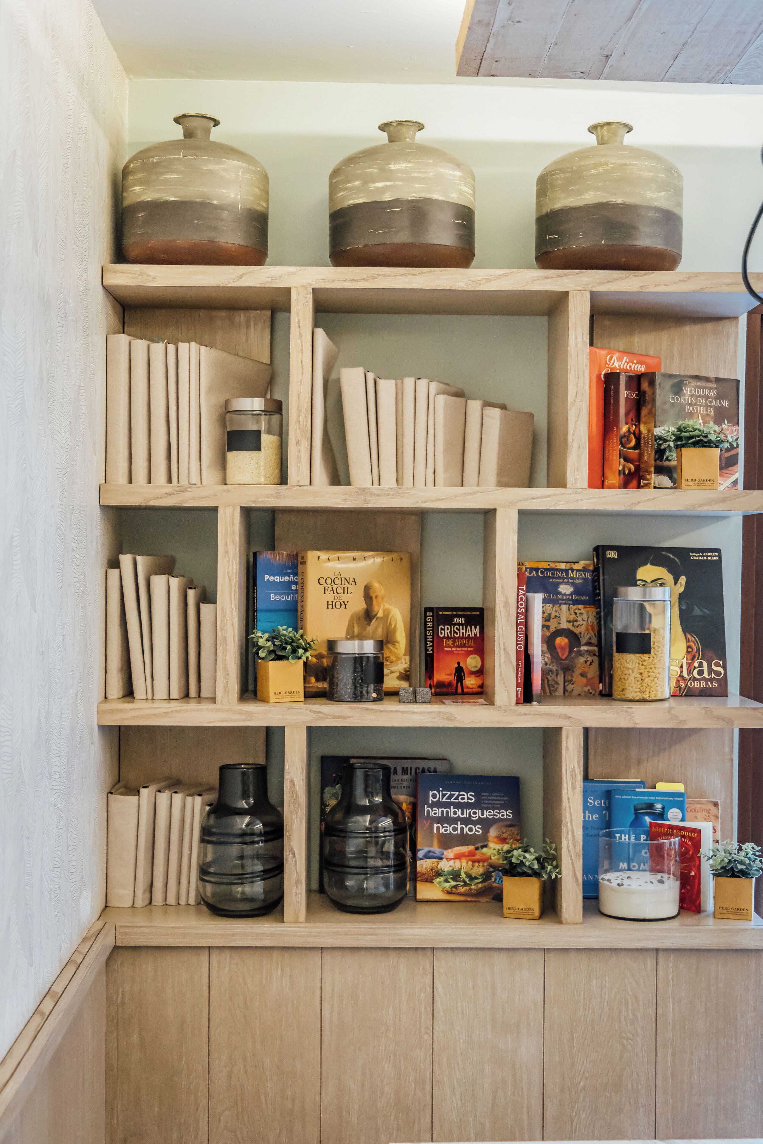 Uma estante com livros de receitas, uma cafeteira e potes decorativos.