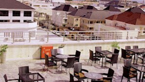 Terraço no telhado com área de estar externa e vista para edifícios ao redor.