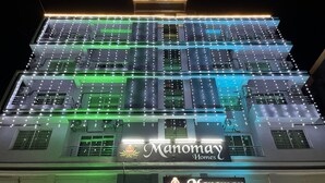 Um edifício com vários andares, iluminado por luzes de fada e com uma placa visível para Manomay Homes.