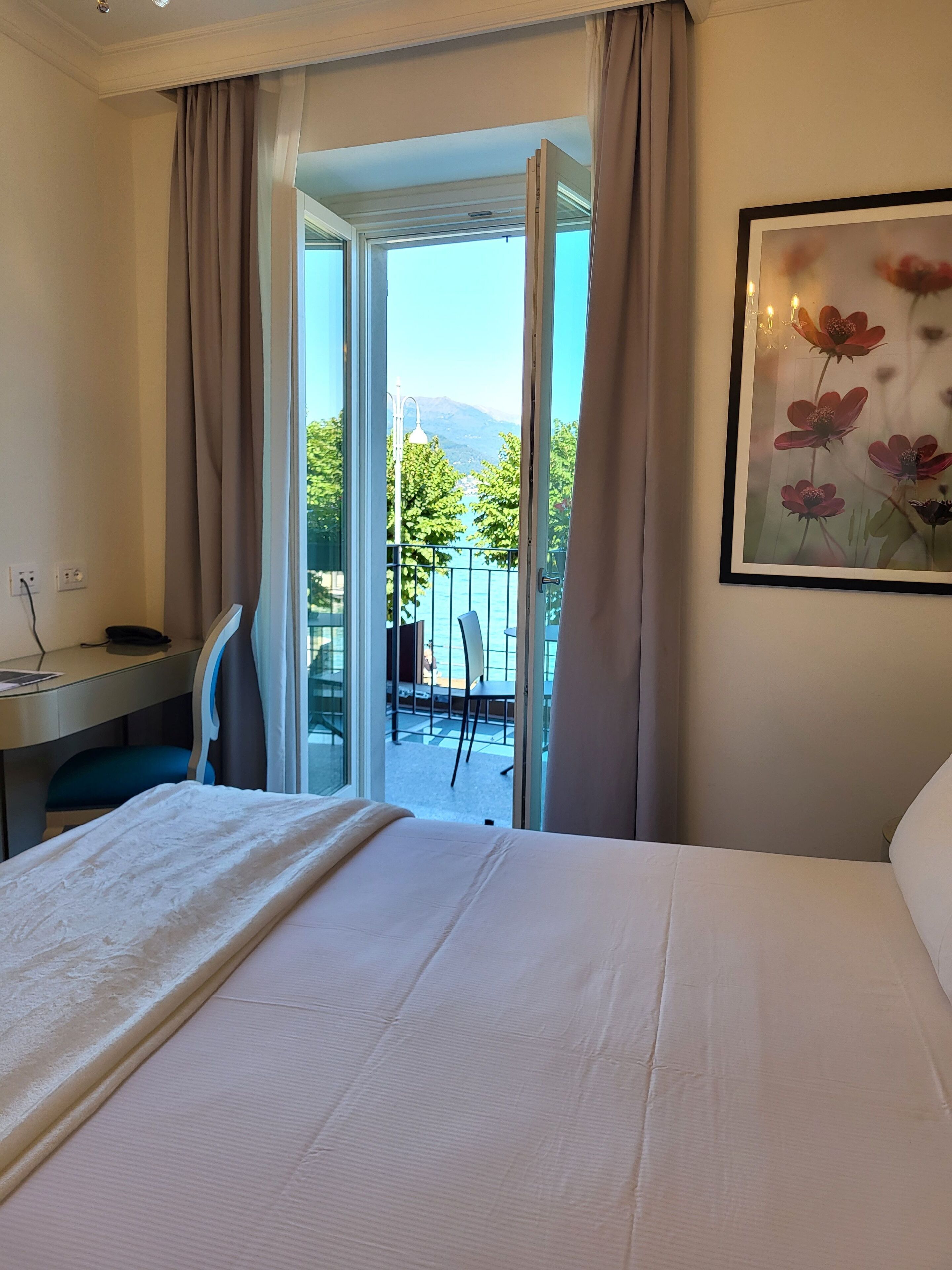 Quarto de hotel com uma cama, uma escrivaninha e vista para uma varanda com área de estar ao ar livre.