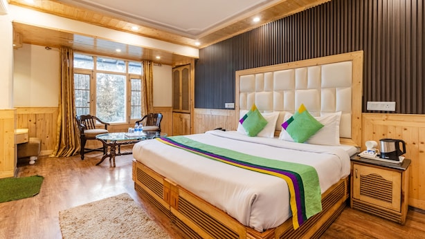 Quarto espaçoso com uma cama grande, cabeceira de madeira e vista para o exterior através de uma janela.