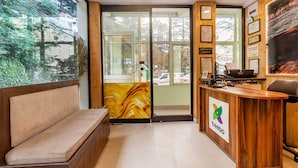 Uma área de recepção com uma mesa de madeira, um banco e vista para uma floresta através de grandes janelas.