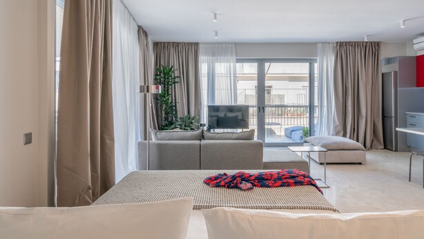 Sala de estar moderna com sofá, mesa de centro e televisão. Varanda com vista para a cidade.