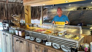 Um balcão de buffet com diversos alimentos e acompanhamentos.